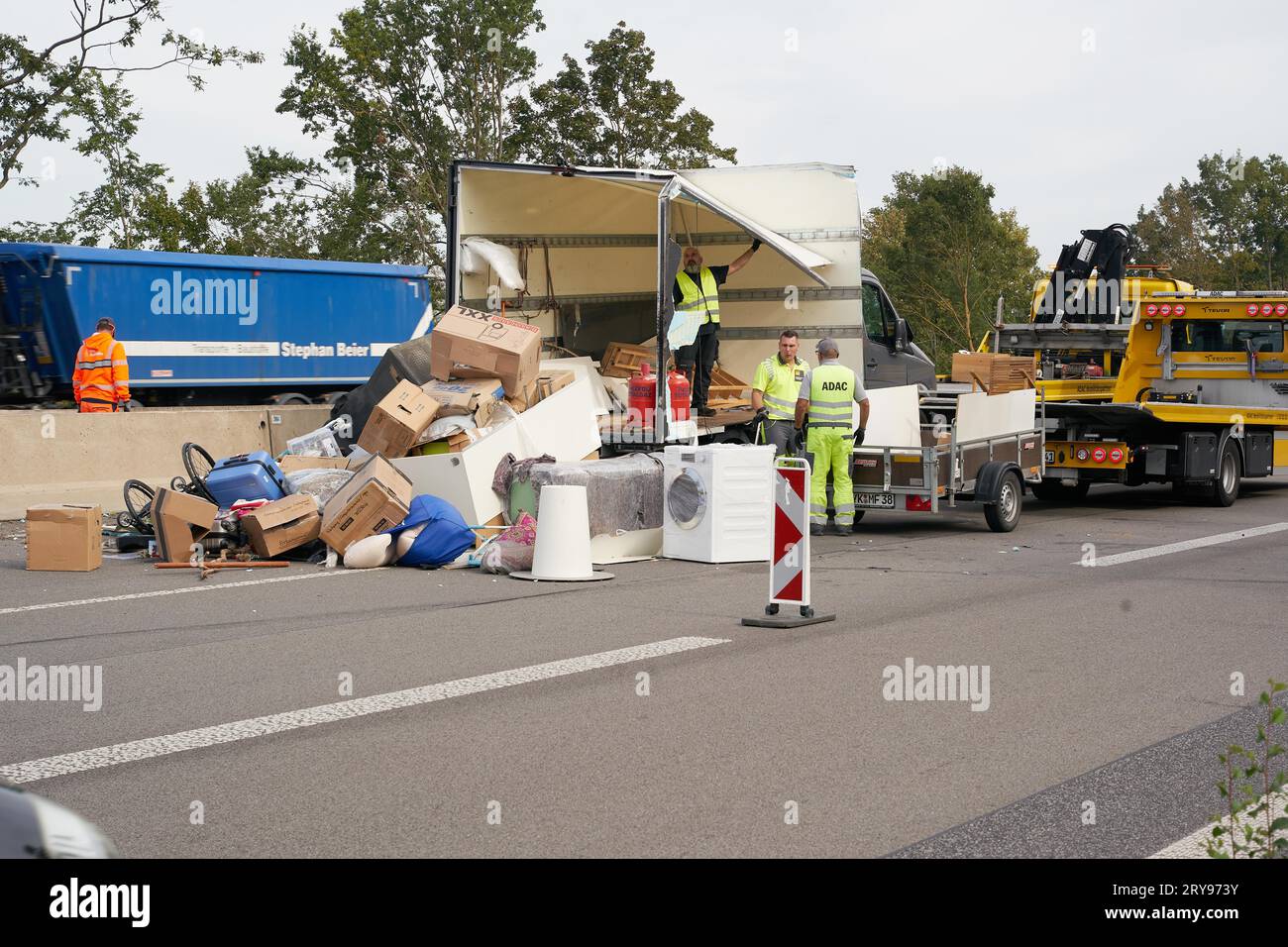 Rescue workers collect the load of a small lorry from the carriageway ...