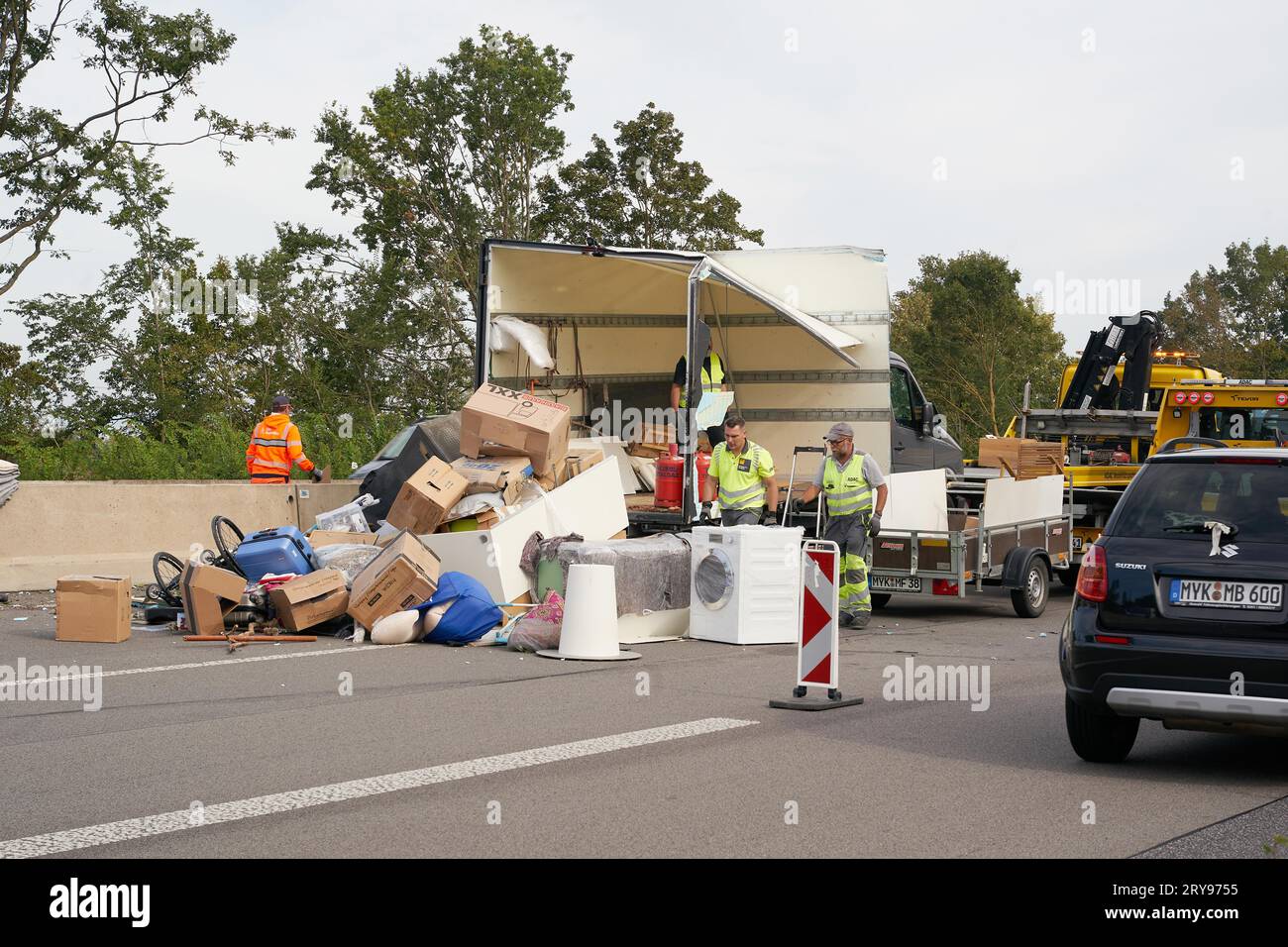 Rescue workers collect the load of a small truck from the carriageway ...