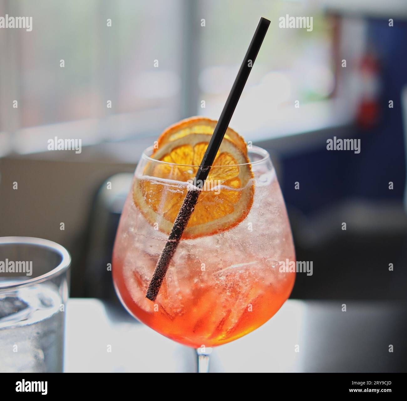 Close up of an aperol spritz with orange slice garnish and a straw, as ...
