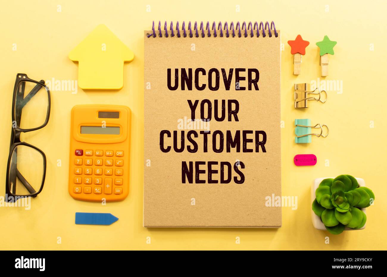 magnifying glass, plant, pen and a white notebook with the text uncover ...