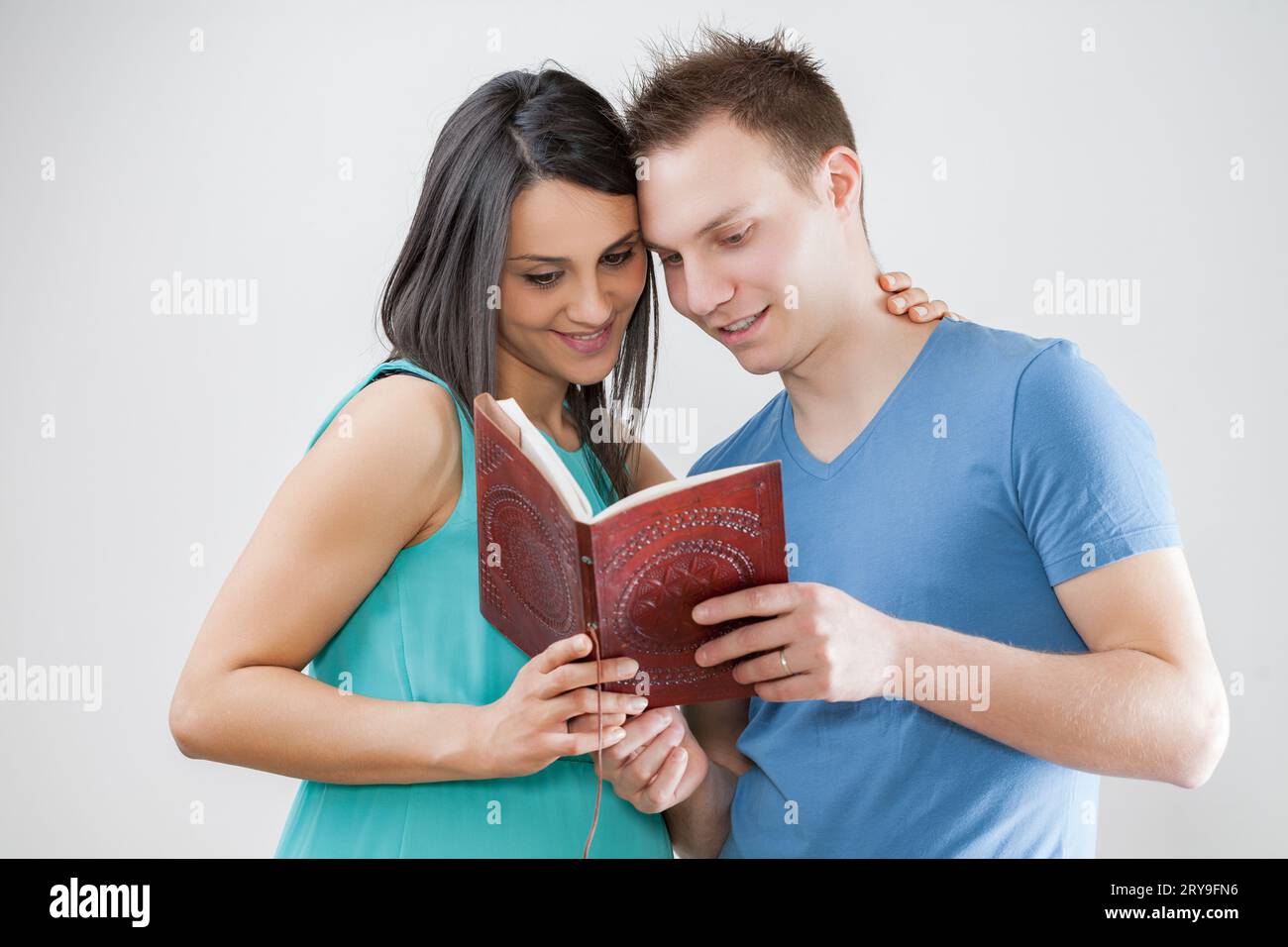 Couple with baby on the way peruse a book. They're engaged in name ...