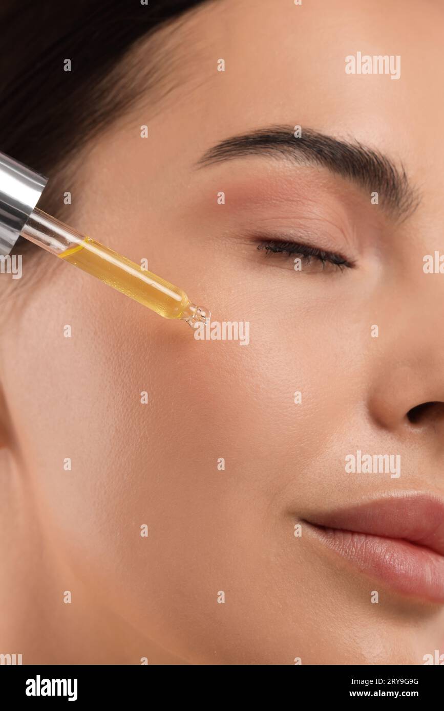 Beautiful young woman applying serum onto her face, closeup Stock Photo ...