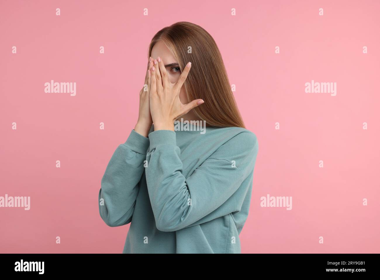 Embarrassed woman covering face with hands on pink background Stock ...