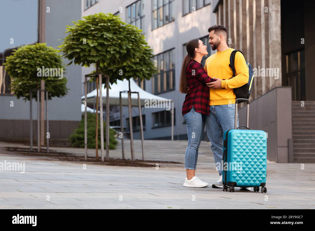 Long-distance relationship. Beautiful couple with luggage hugging outdoors Stock Photo - Alamy