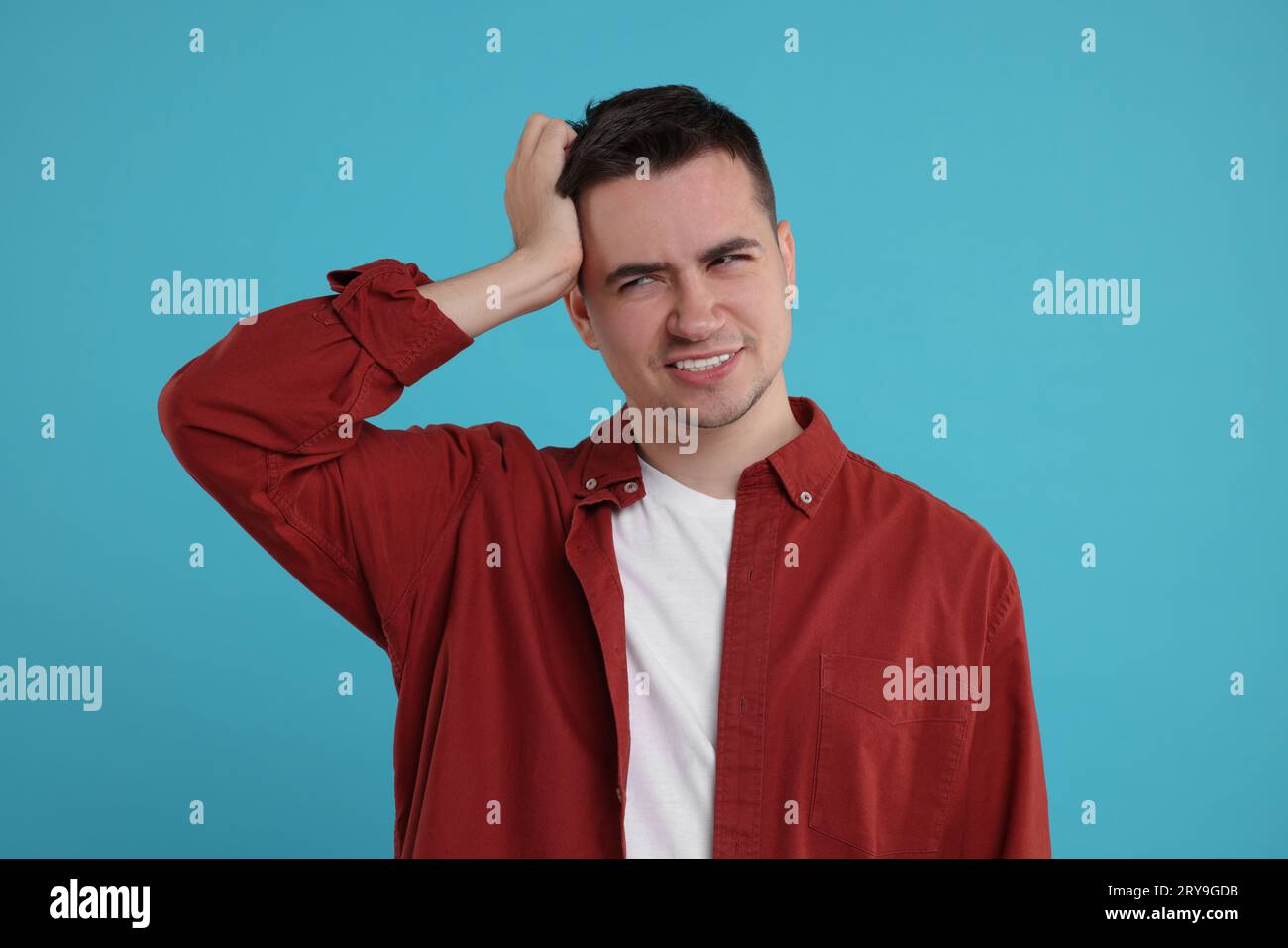 Portrait of embarrassed young man on light blue background Stock Photo ...