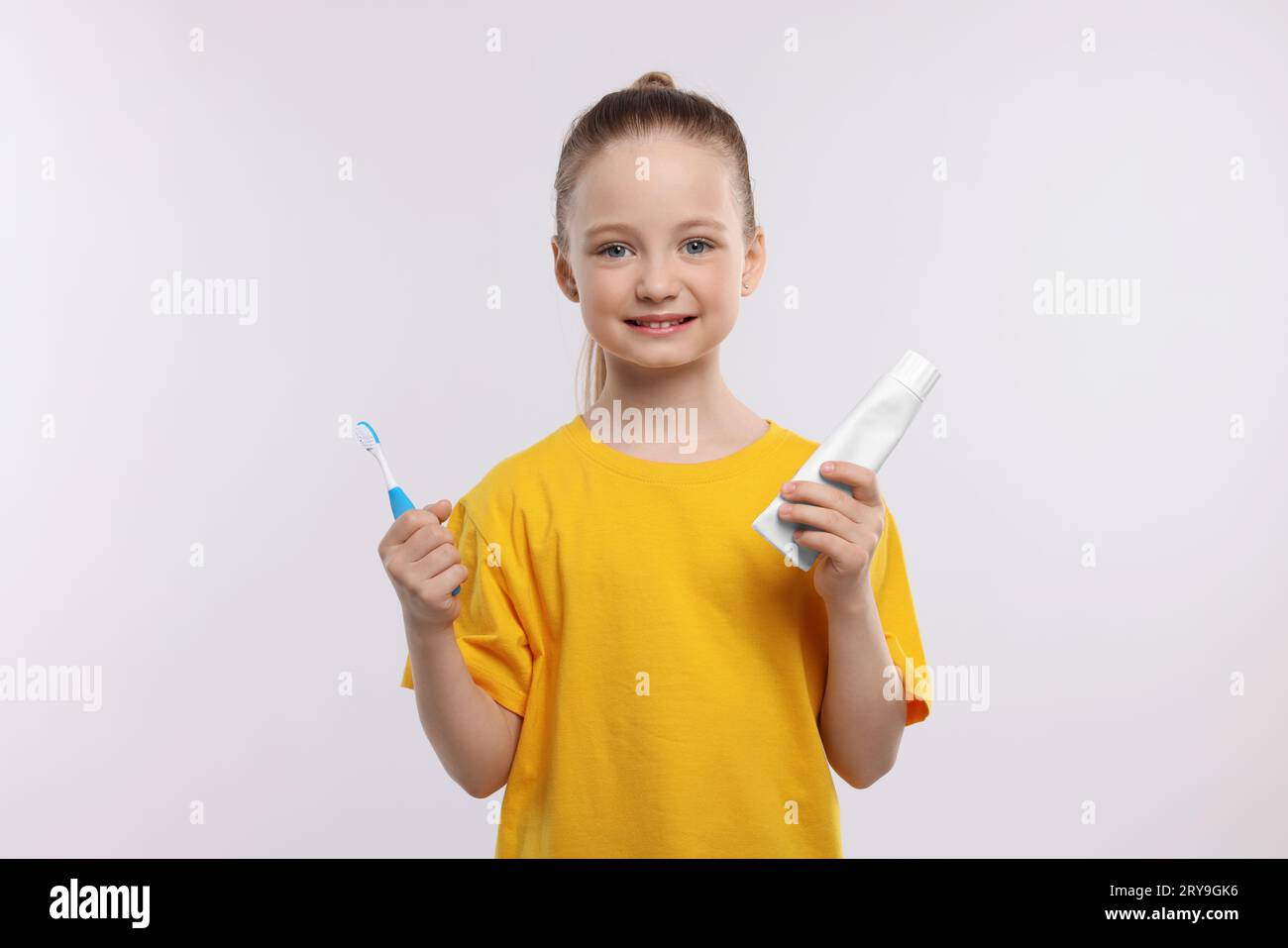 Happy girl holding toothbrush and tube of toothpaste on white ...