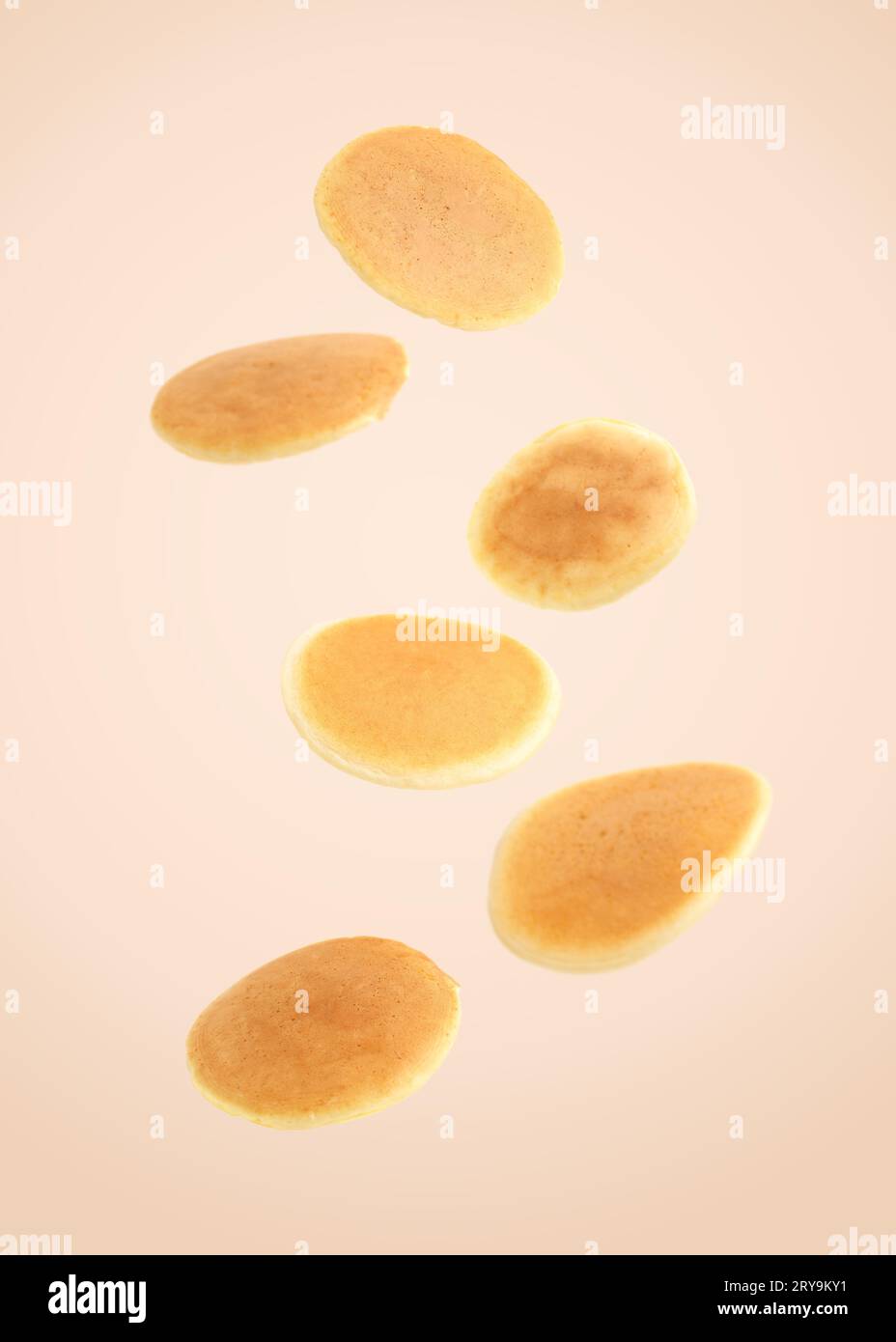 Tasty fresh pancakes falling on beige background Stock Photo - Alamy