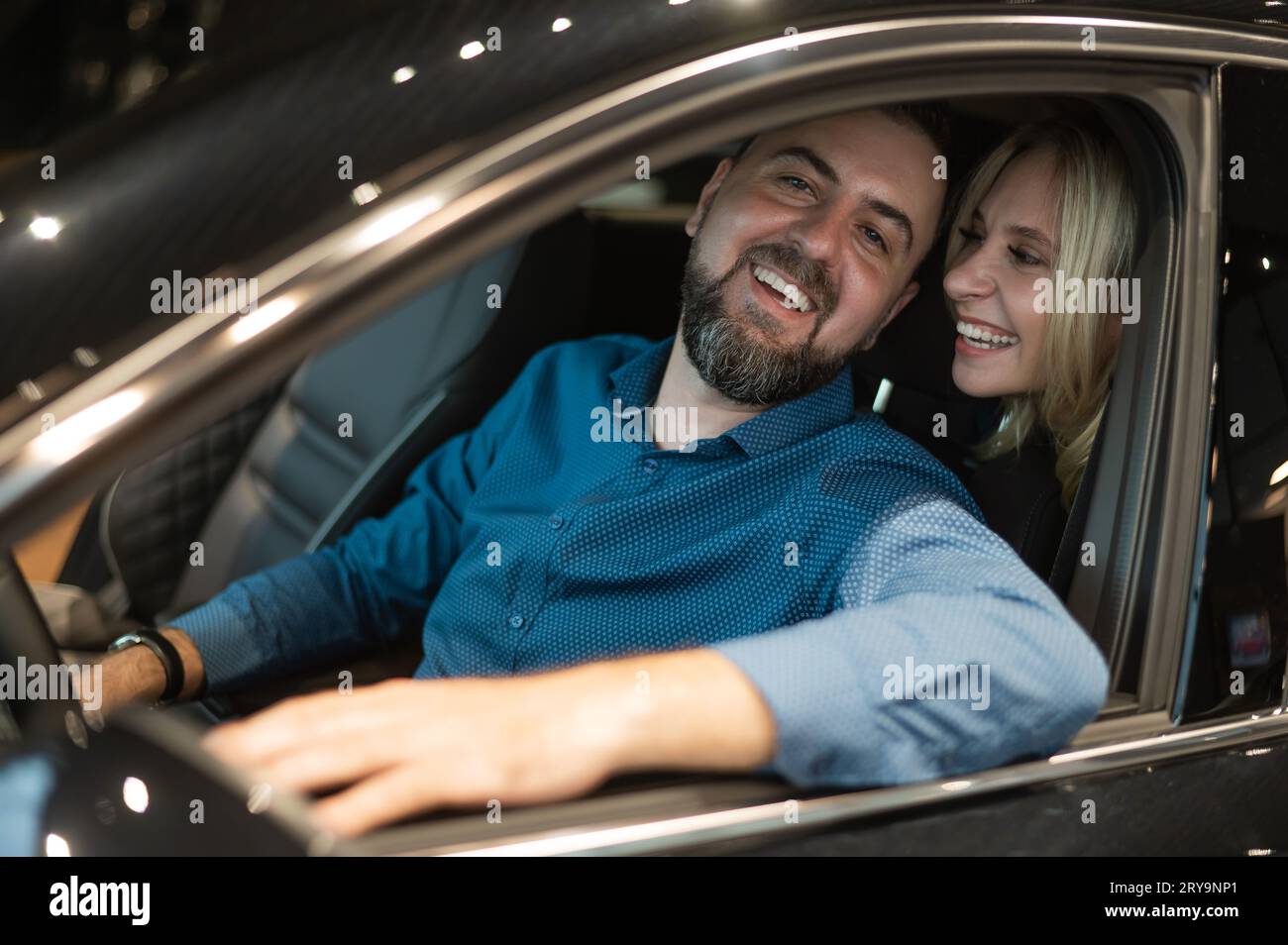 Happy married couple testing new car in car showroom Stock Photo - Alamy