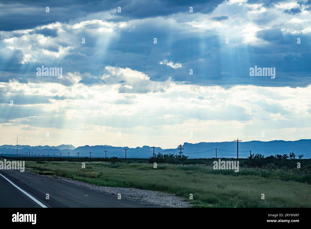 sunbeams through clouds shine on silhouetted telephone poles Stock ...
