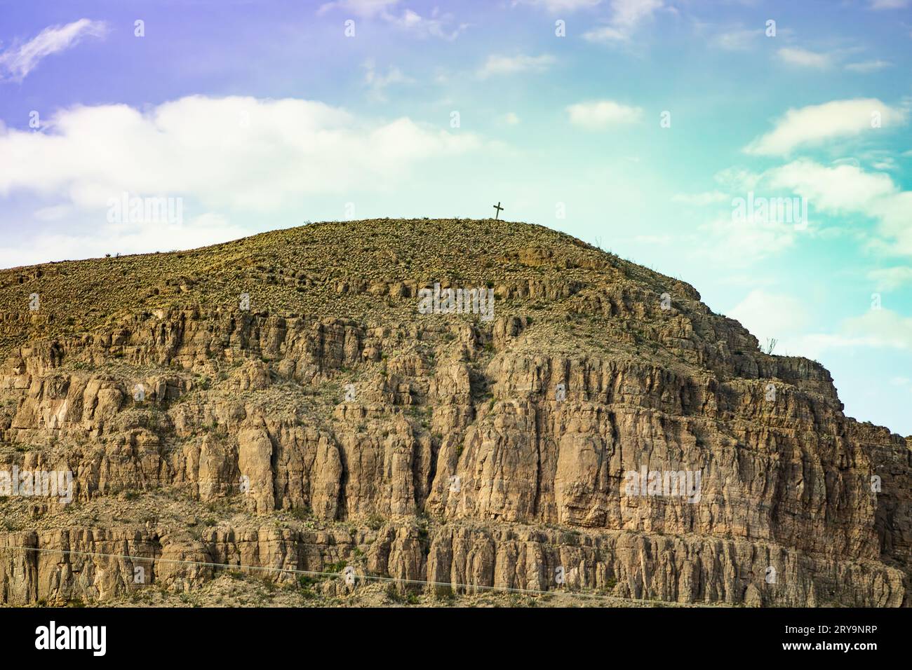 A colorful tinted sky behind a lone cross on a rocky hill Stock Photo ...