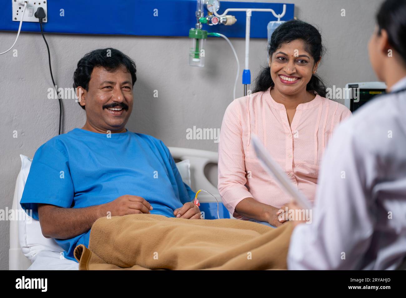 Shoulder shot of friendly indian doctor talking with recovered patient ...