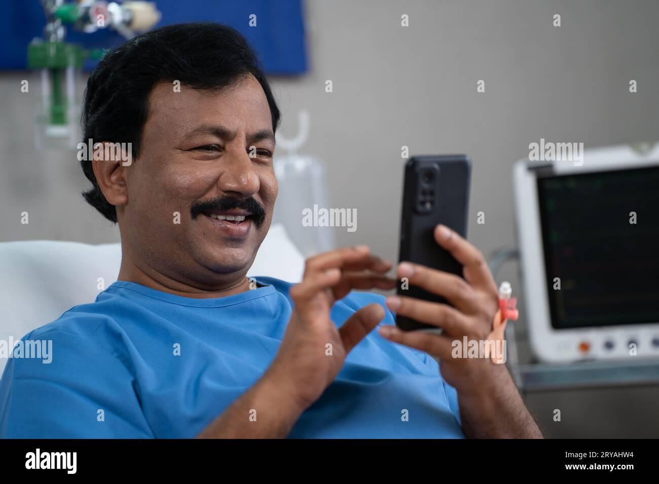 Indian admitted recovered patient using mobile phone on hospital bed ...