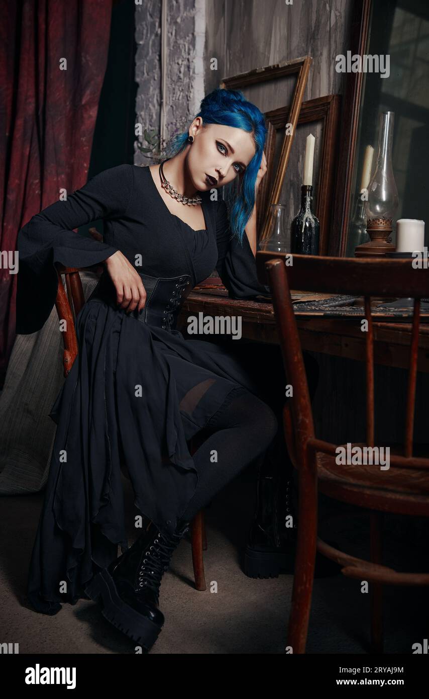 Indoors portrait of beautiful goth girl in black dress. Blue-haired ...