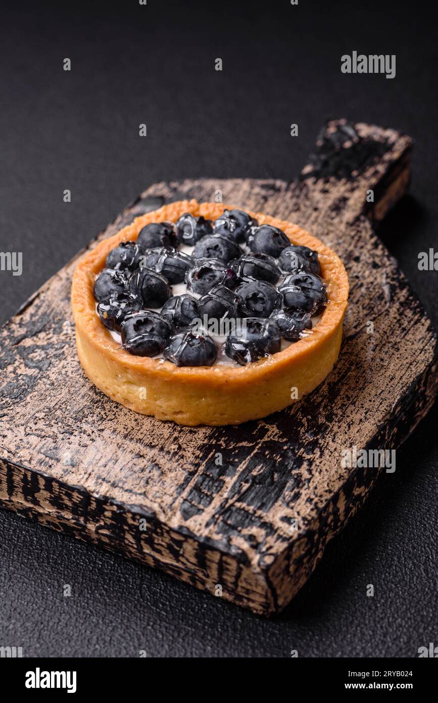 Delicious fresh sweet round tart with ripe blueberries and cream on a ...