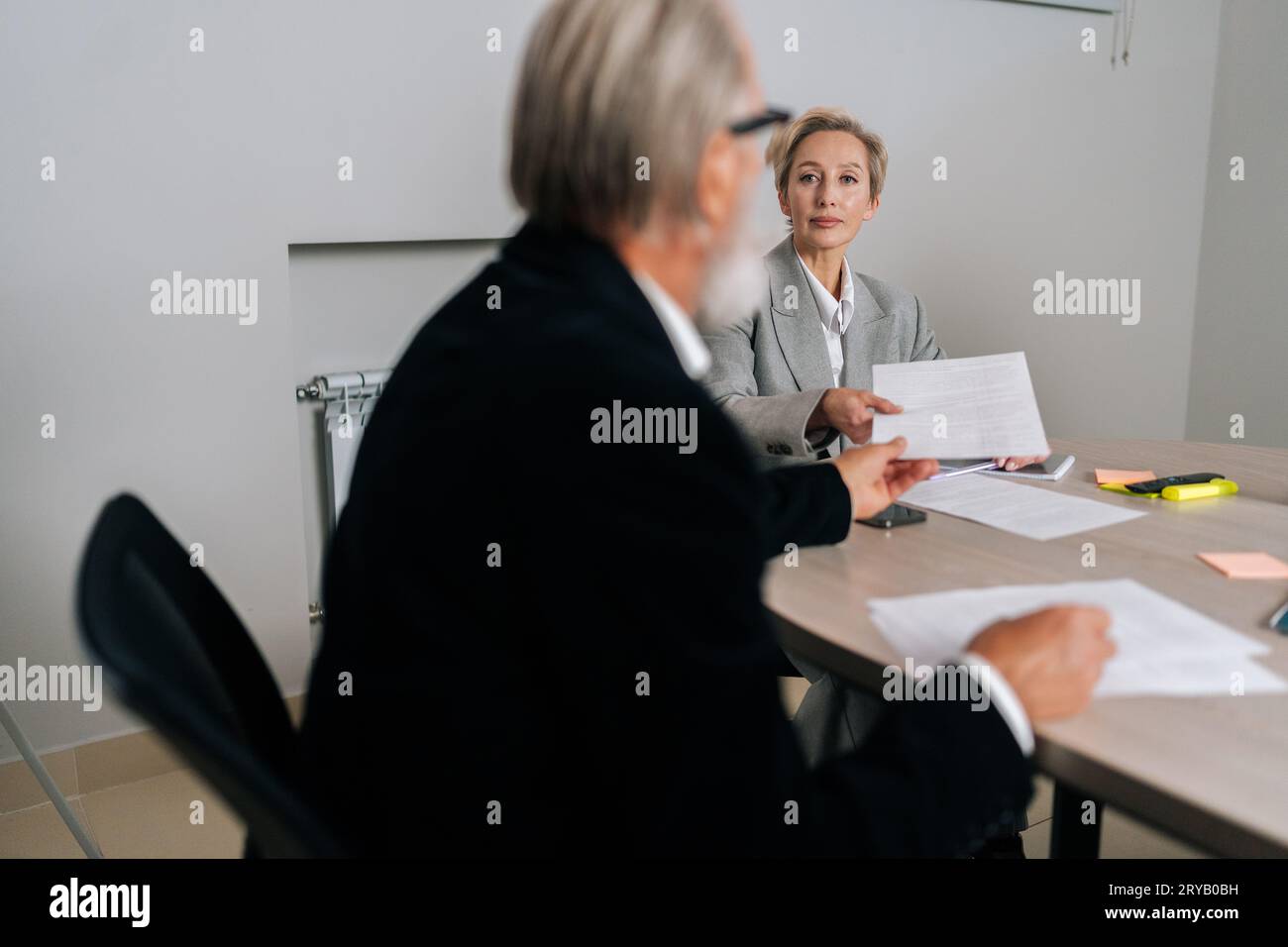 Back view of mature adult male boss team leader giving paper report ...