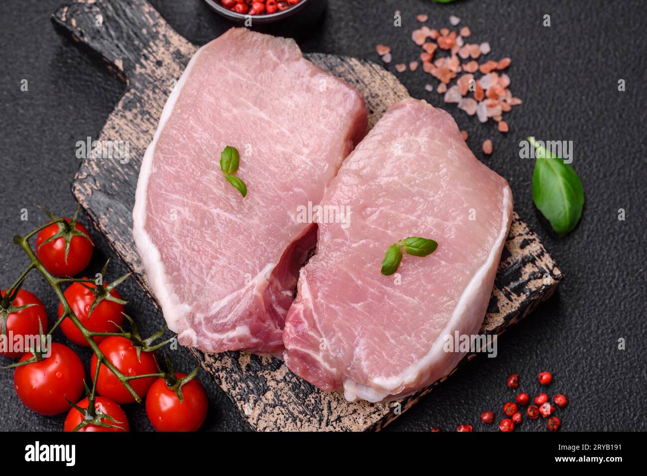 Raw fresh pork meat steak with salt, spices and herbs on a wooden ...