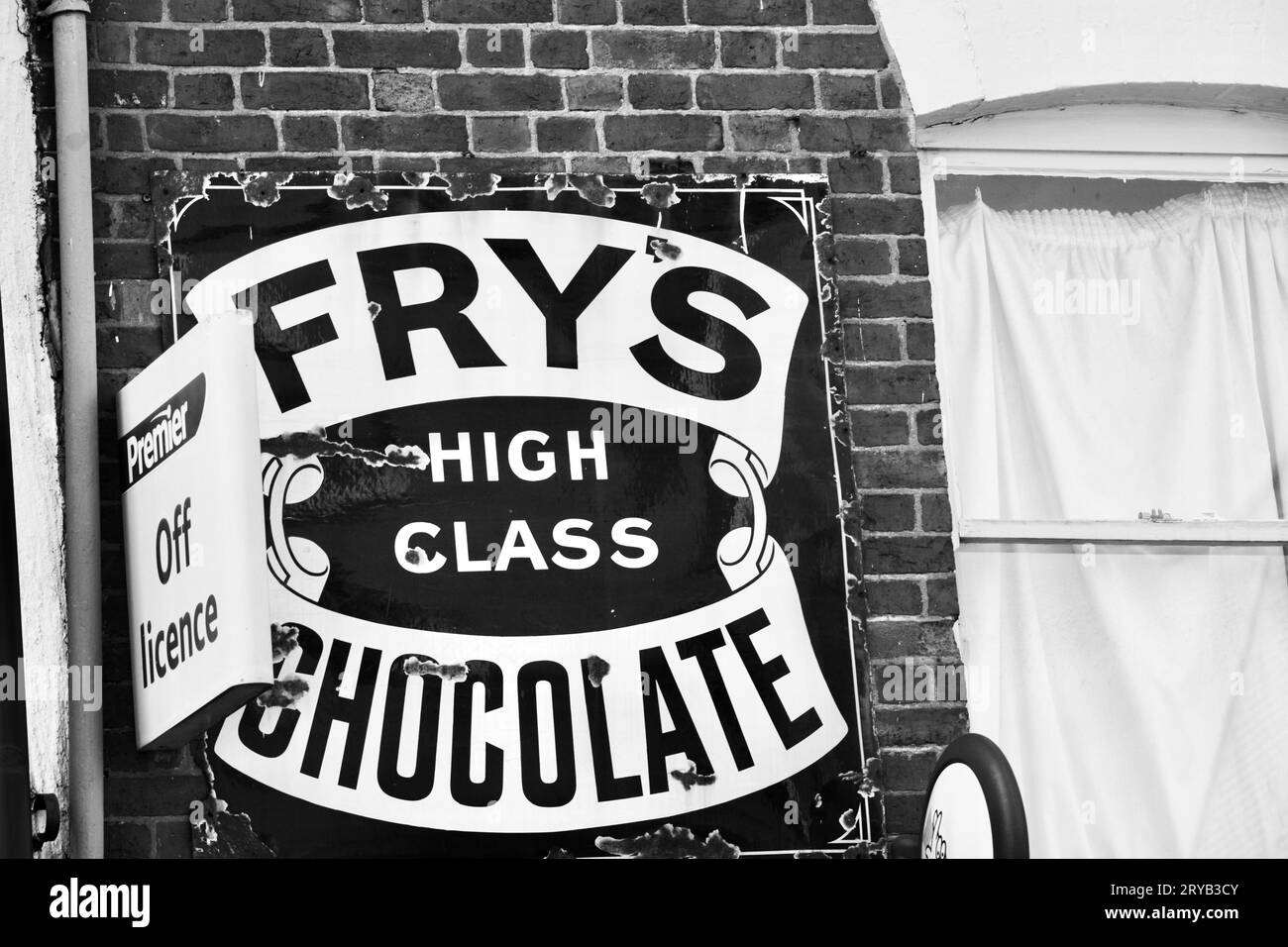 A colourful, vintage, metal advertising sign displayed on a brick wall ...