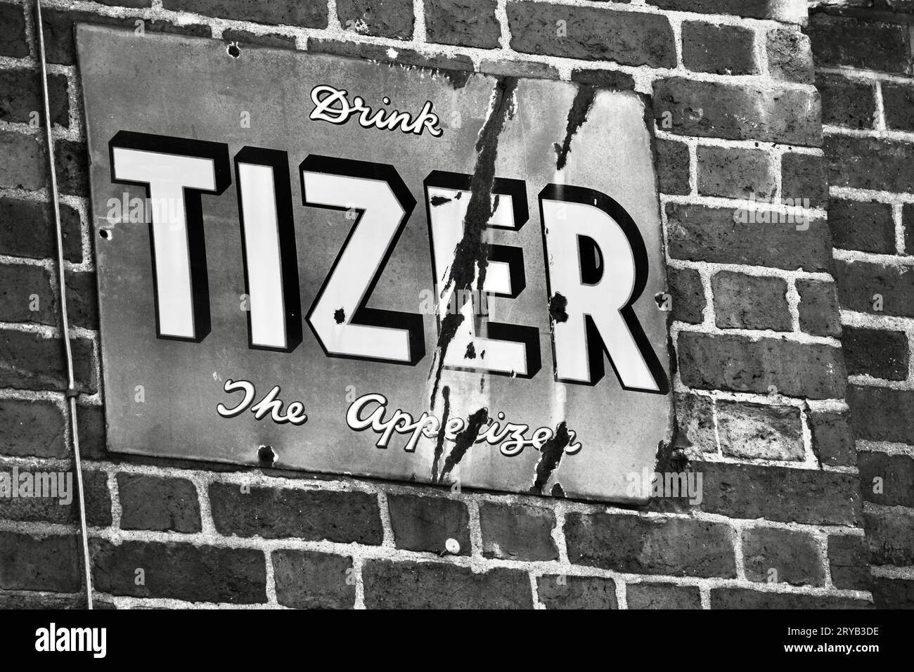 A black and white photo of a vintage metal sign advertising Tizer, a ...