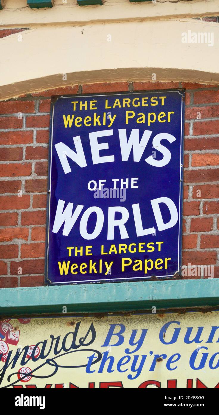 A colourful, vintage, metal advertising sign displayed on a brick wall ...