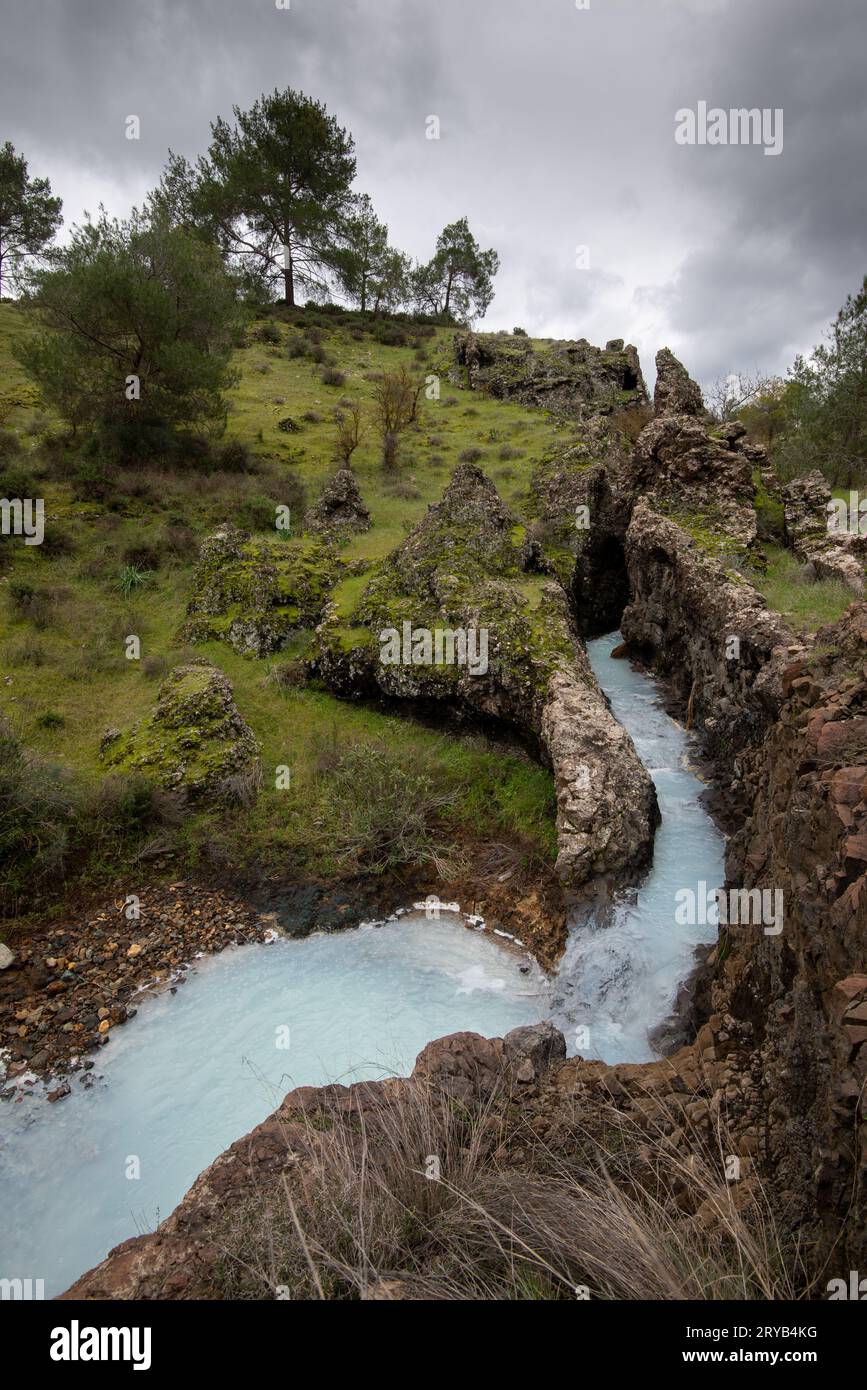 Blue toxic water flowing through a rock formation. Pollution in nature ...
