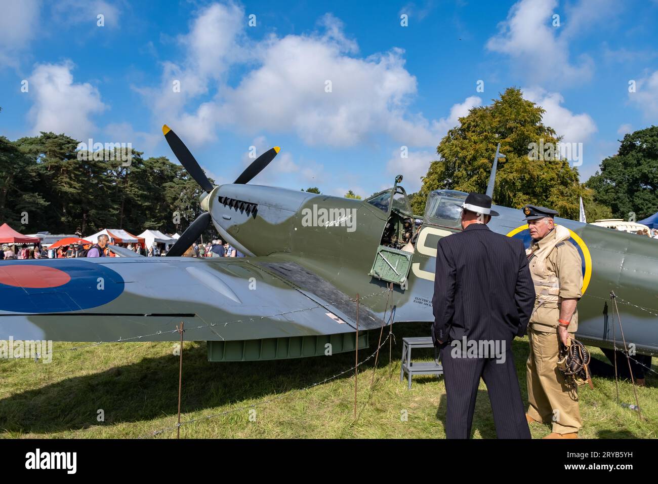 Holt, Norfolk, UK – September 16 2023. Two men dressed in 1940s attire talking beside a World ...