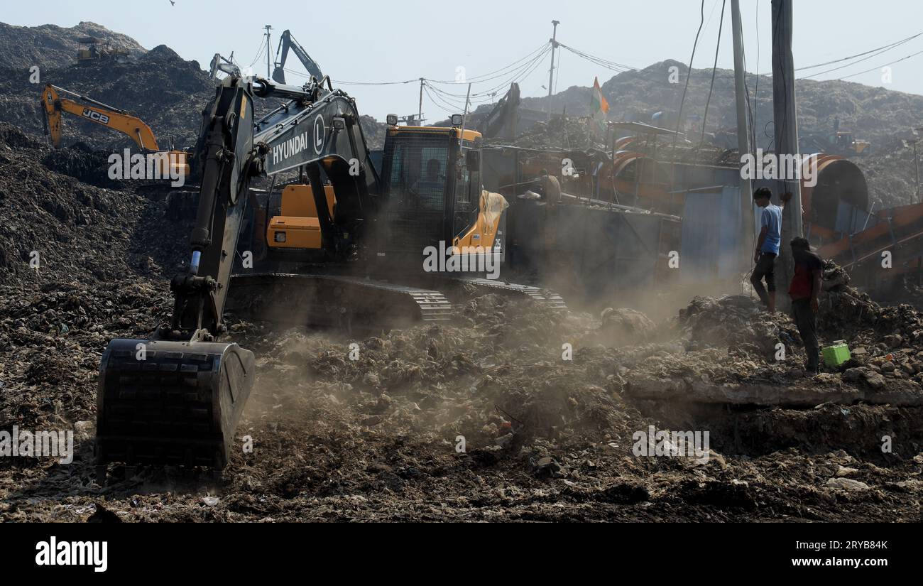 A JCB excavator crane machine lifting garbage from the Bhalswa landfill ...