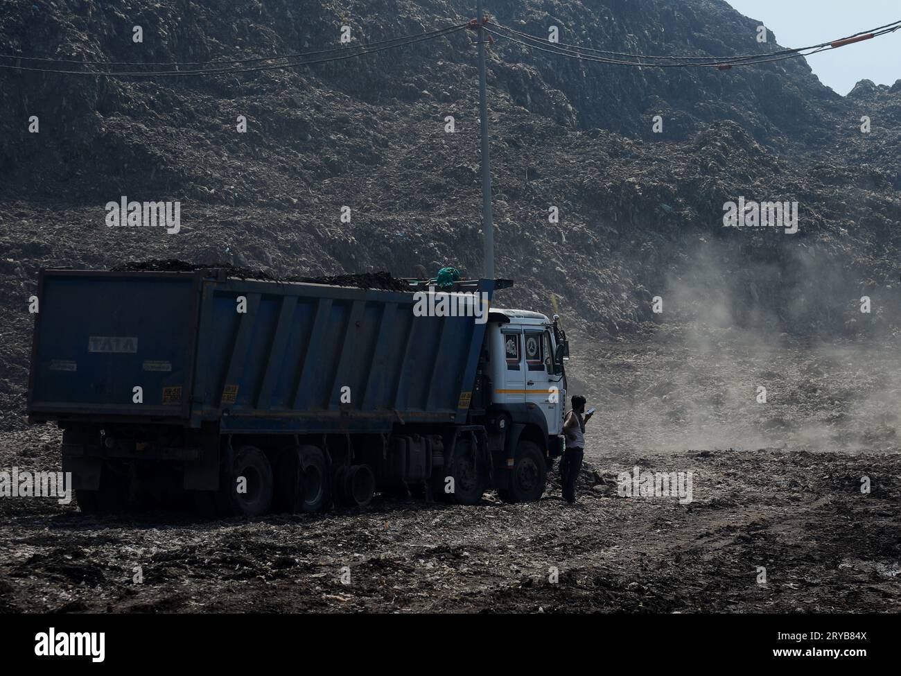 A man stand next to a garbage dumper truck at the Bhalswa landfill site ...