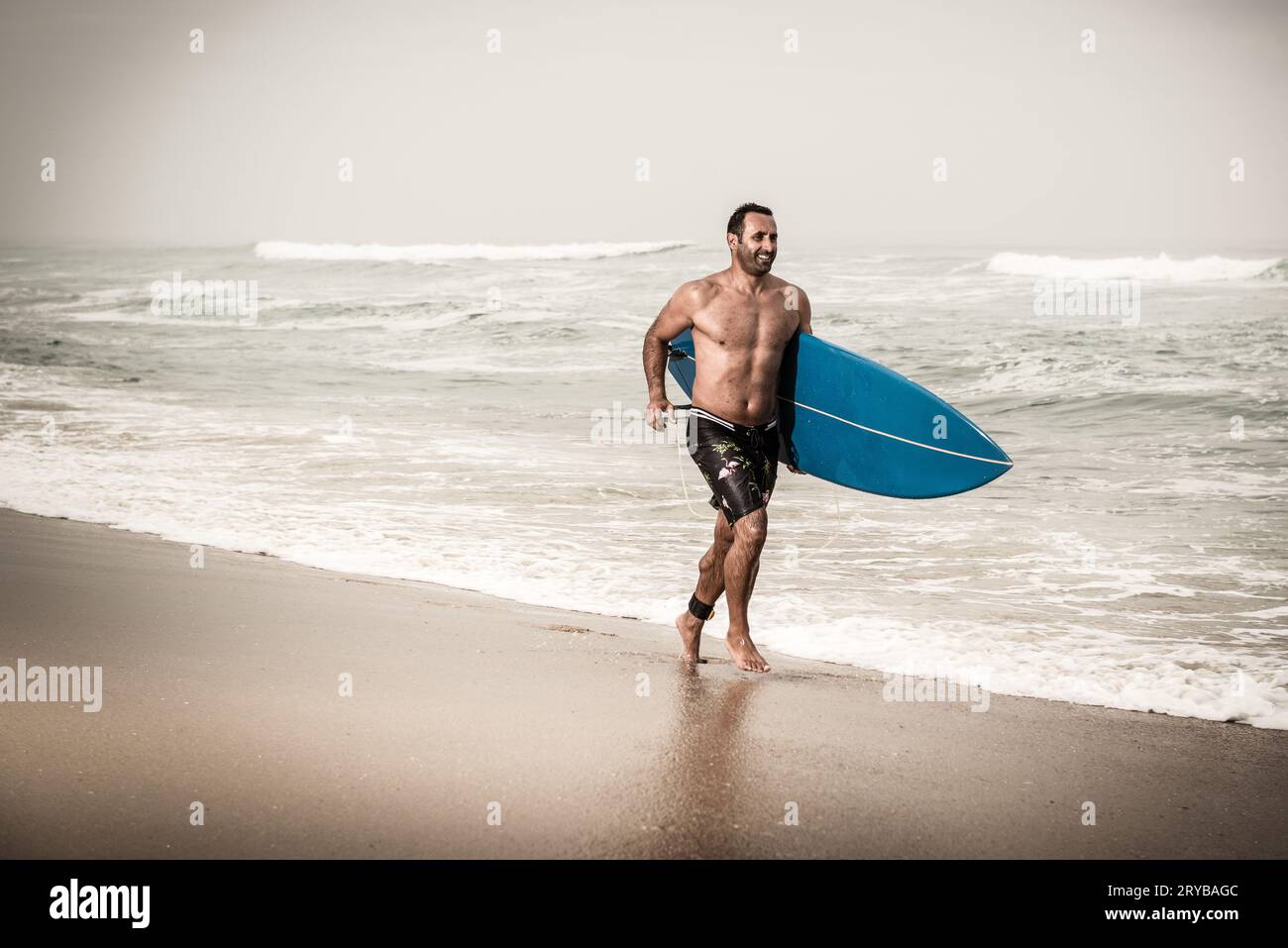 Surfer running on the beach Stock Photo - Alamy