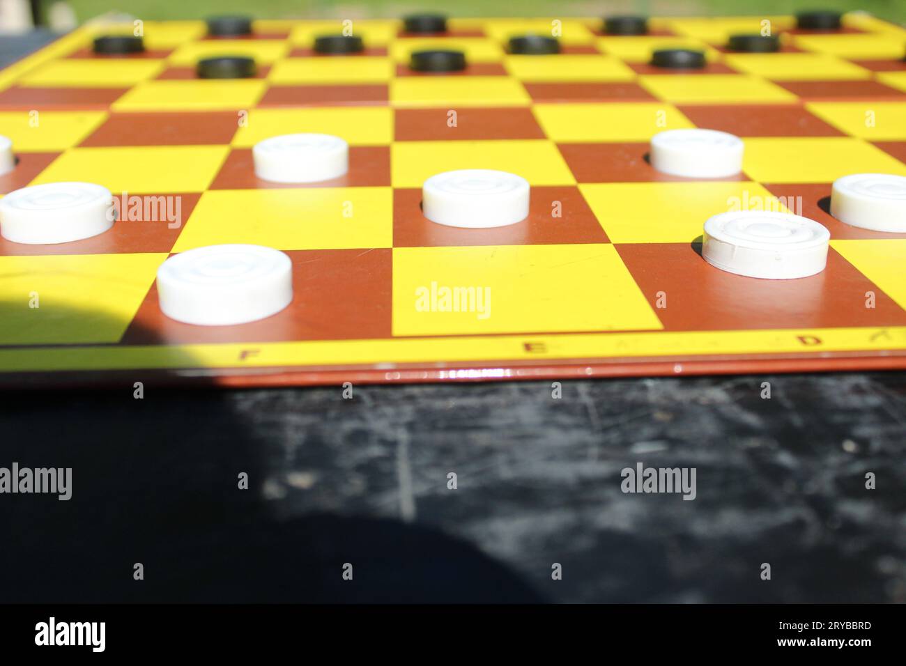 A game of checkers. checkers on a yellow brown chessboard. Street games ...