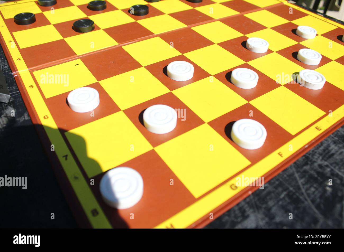 A game of checkers. checkers on a yellow brown chessboard. Street games ...