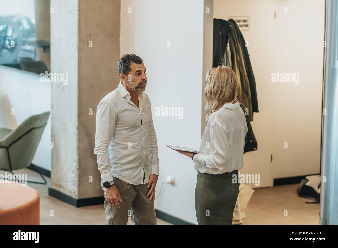 Middle-aged, blonde secretary talking to her 50s boss Stock Photo - Alamy