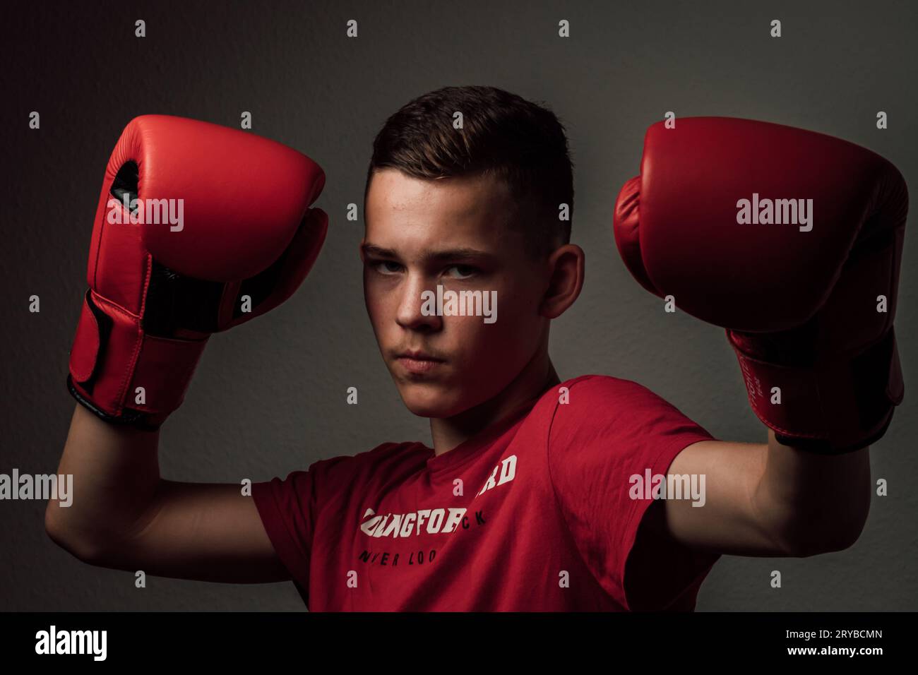A teenage boxer athlete is training to box on dark background ...