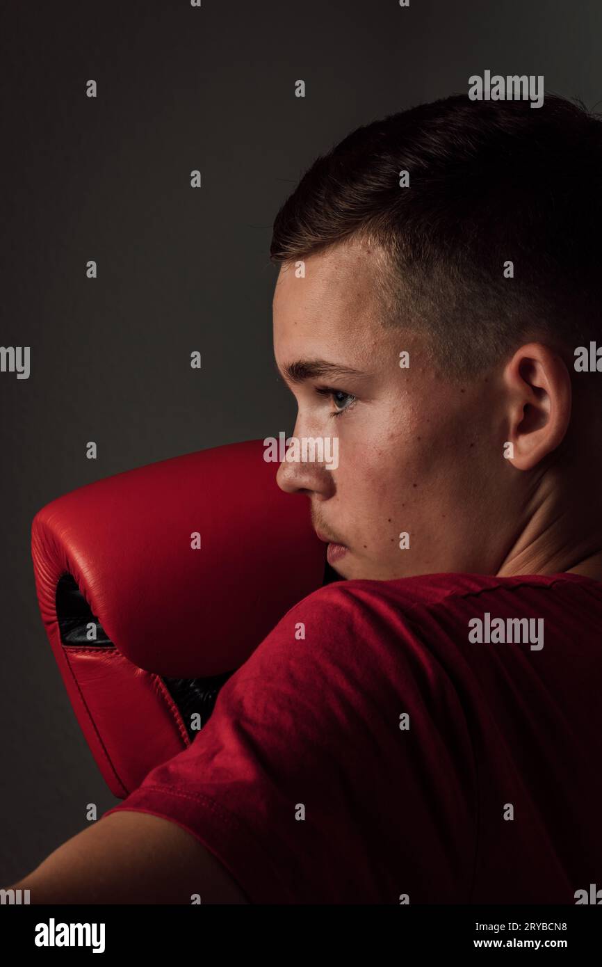 A teenage boxer athlete is training to box on dark background ...