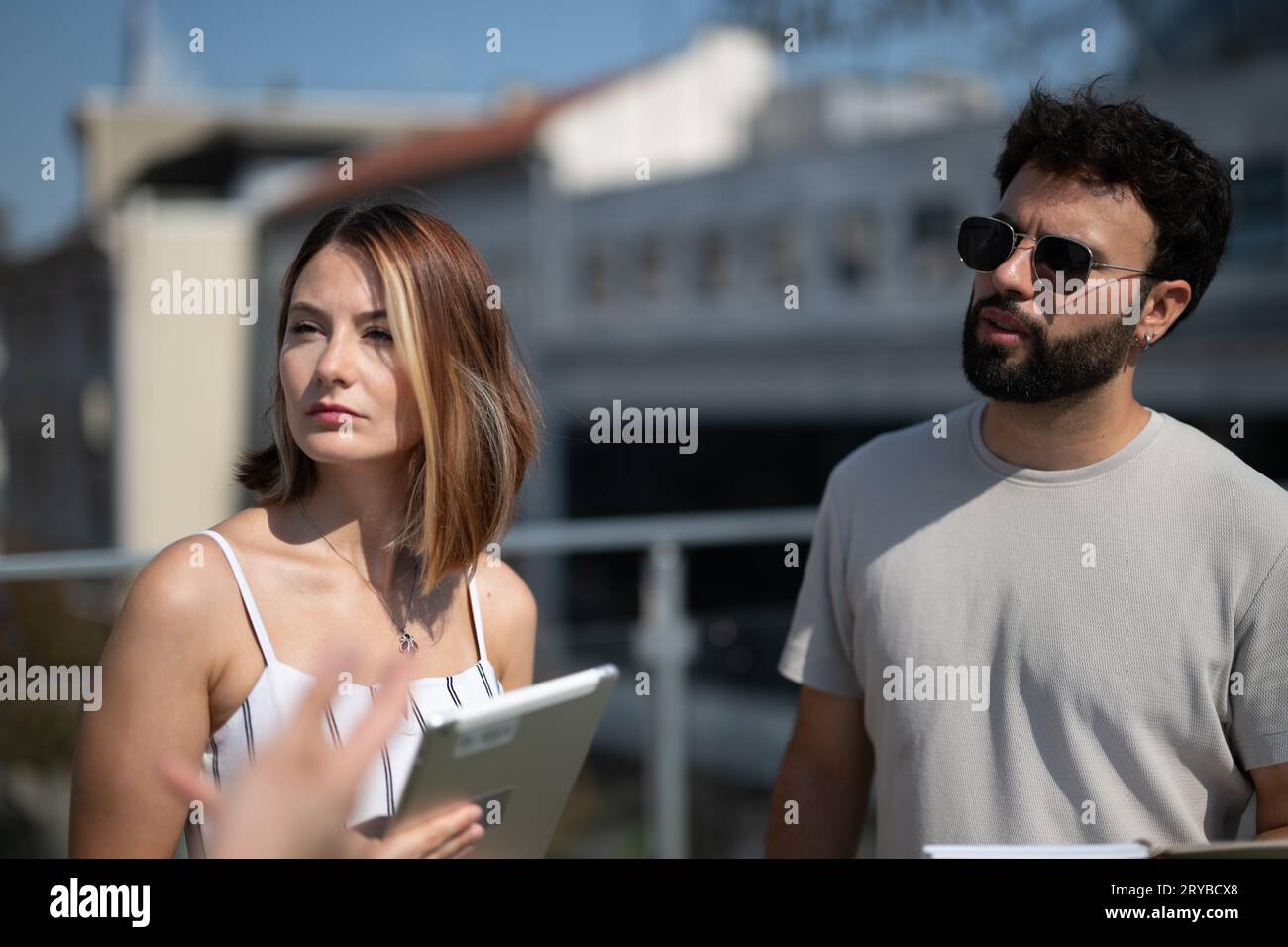 Architectural team discussing blueprint outdoors, working together on a modern building design ...