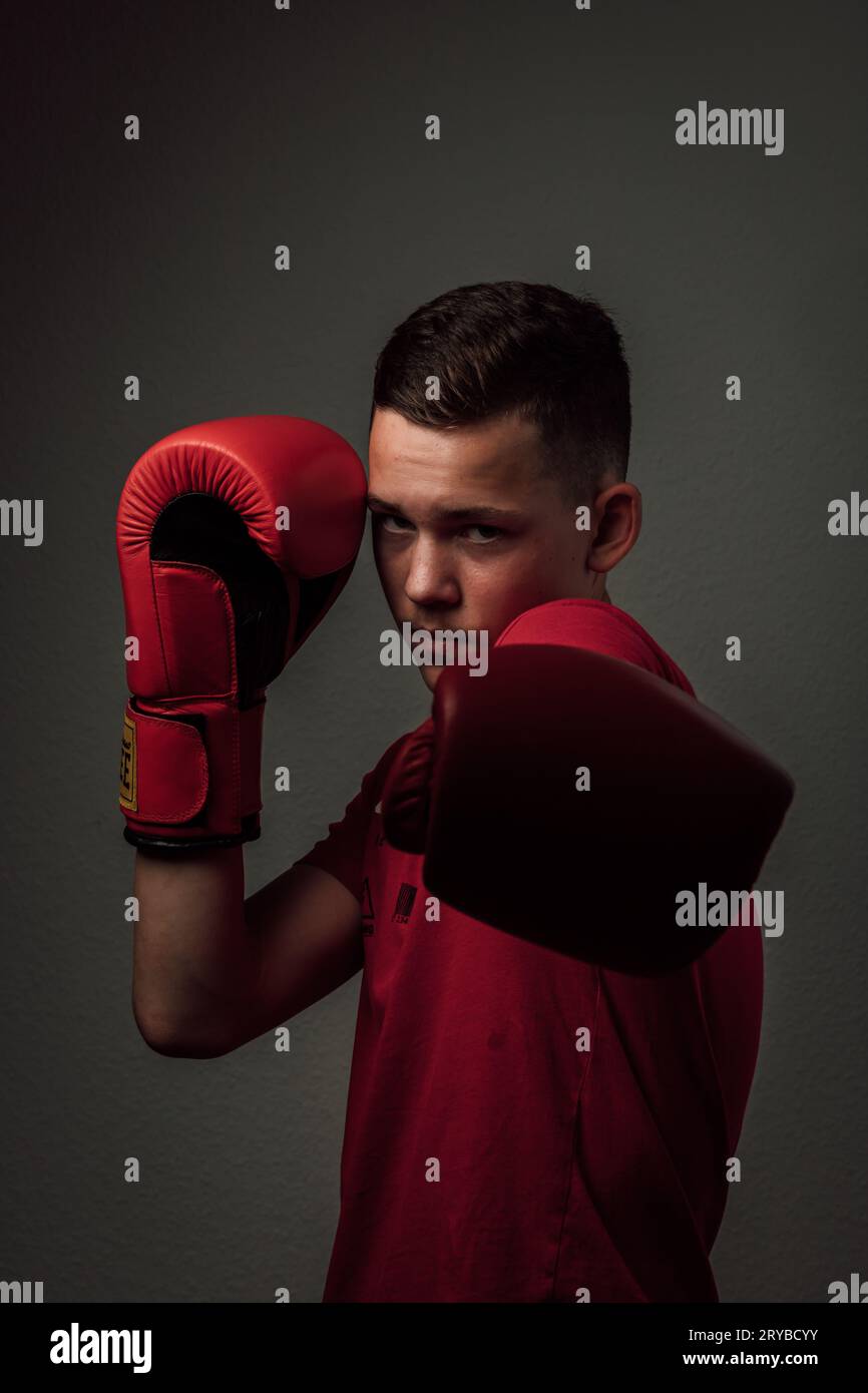 A teenage boxer athlete is training to box on dark background ...