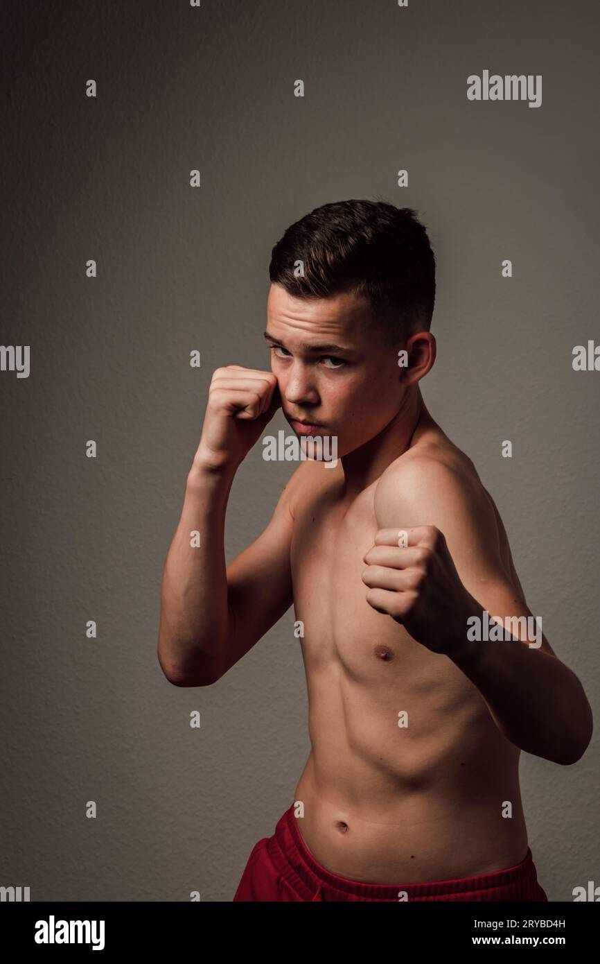 A teenage boxer athlete is training to box on dark background ...
