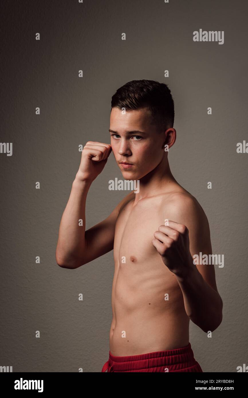A teenage boxer athlete is training to box on dark background ...