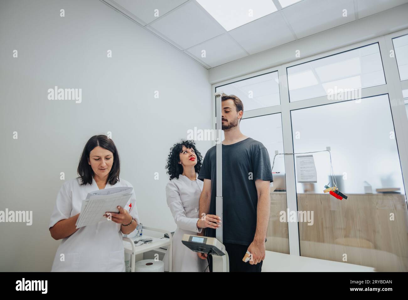 A confident and successful female physicians measure patient height and ...