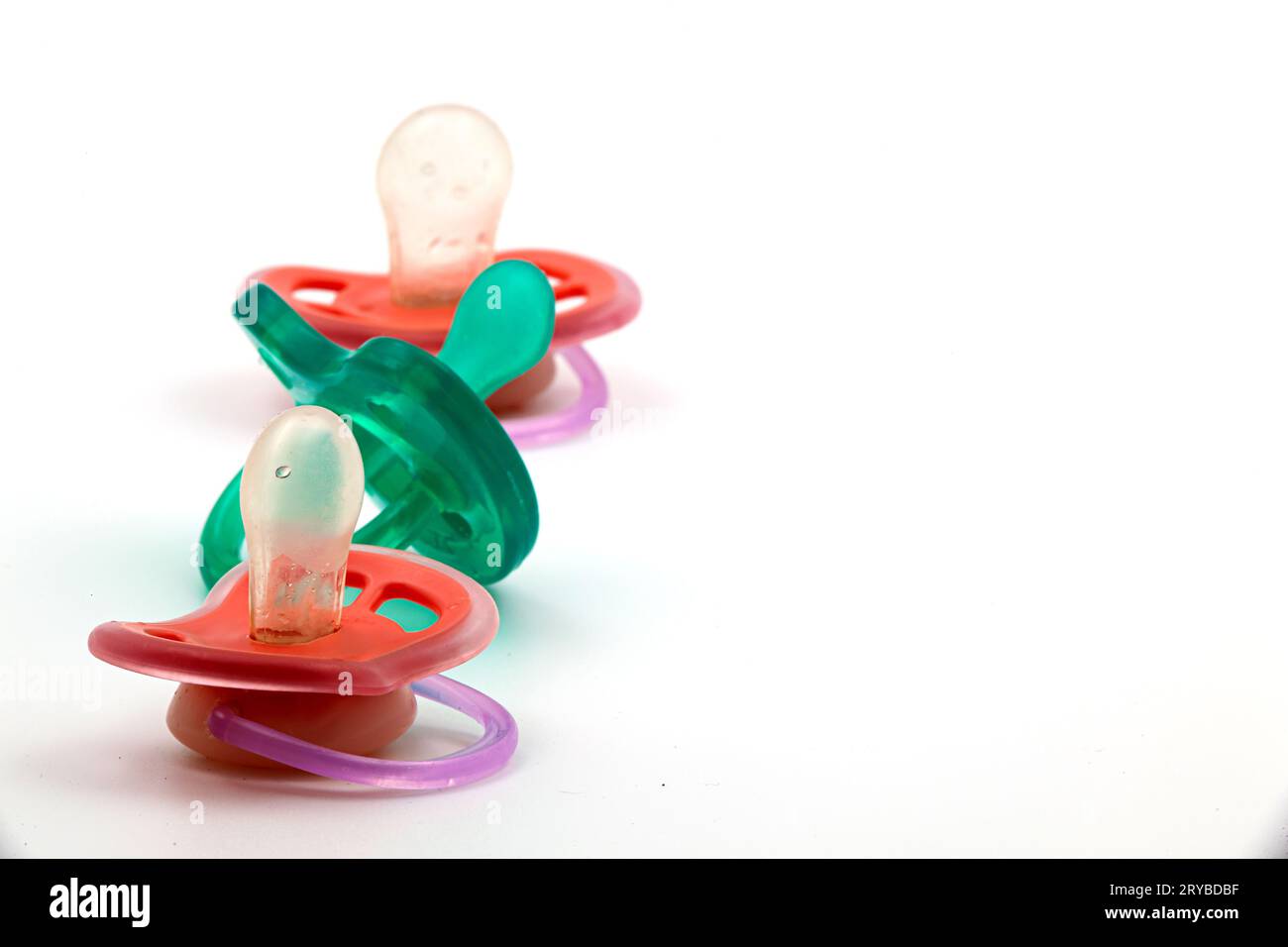 Two pink pacifiers and one turquoise pacifier for newborn on white ...