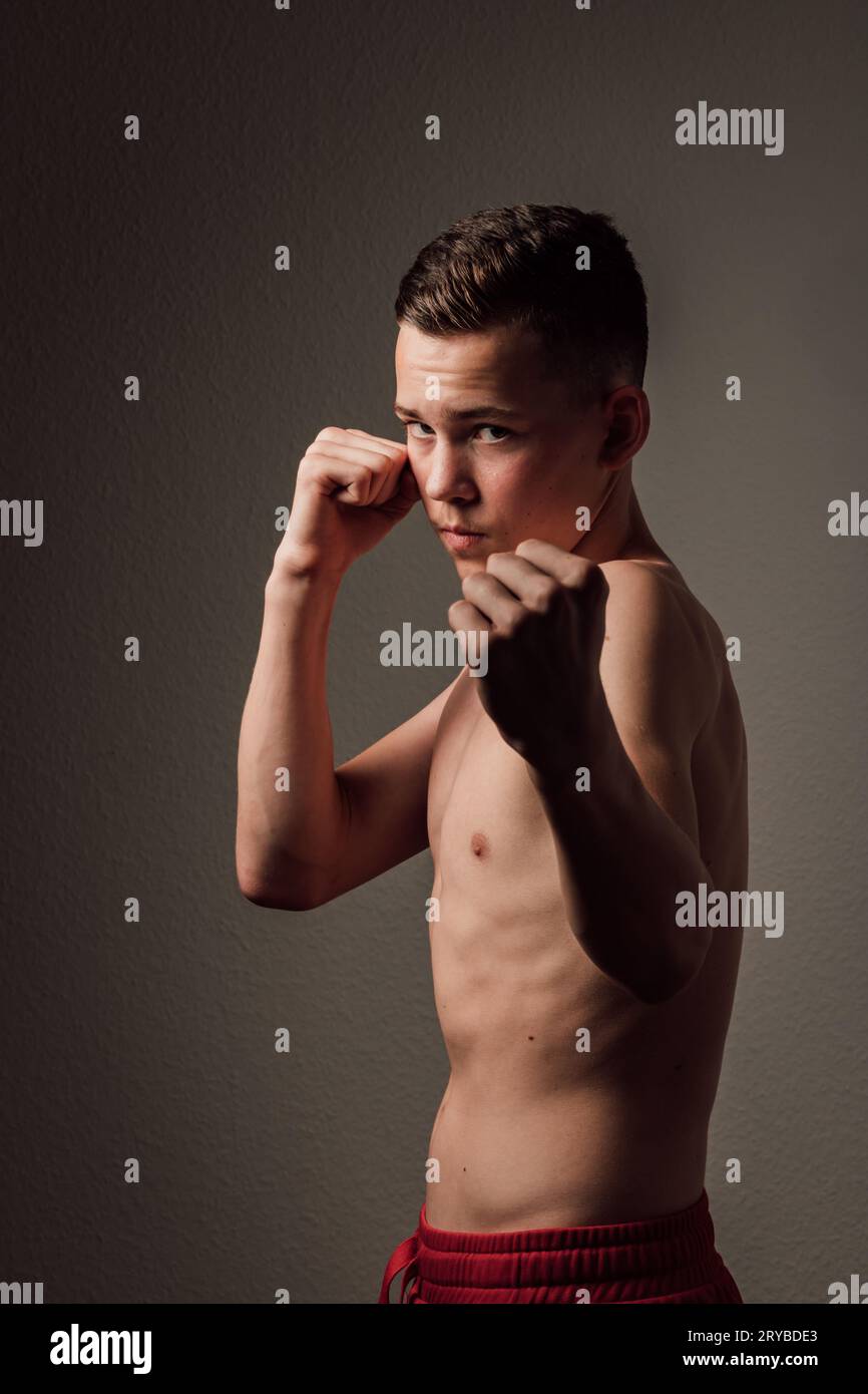 A teenage boxer athlete is training to box on dark background ...