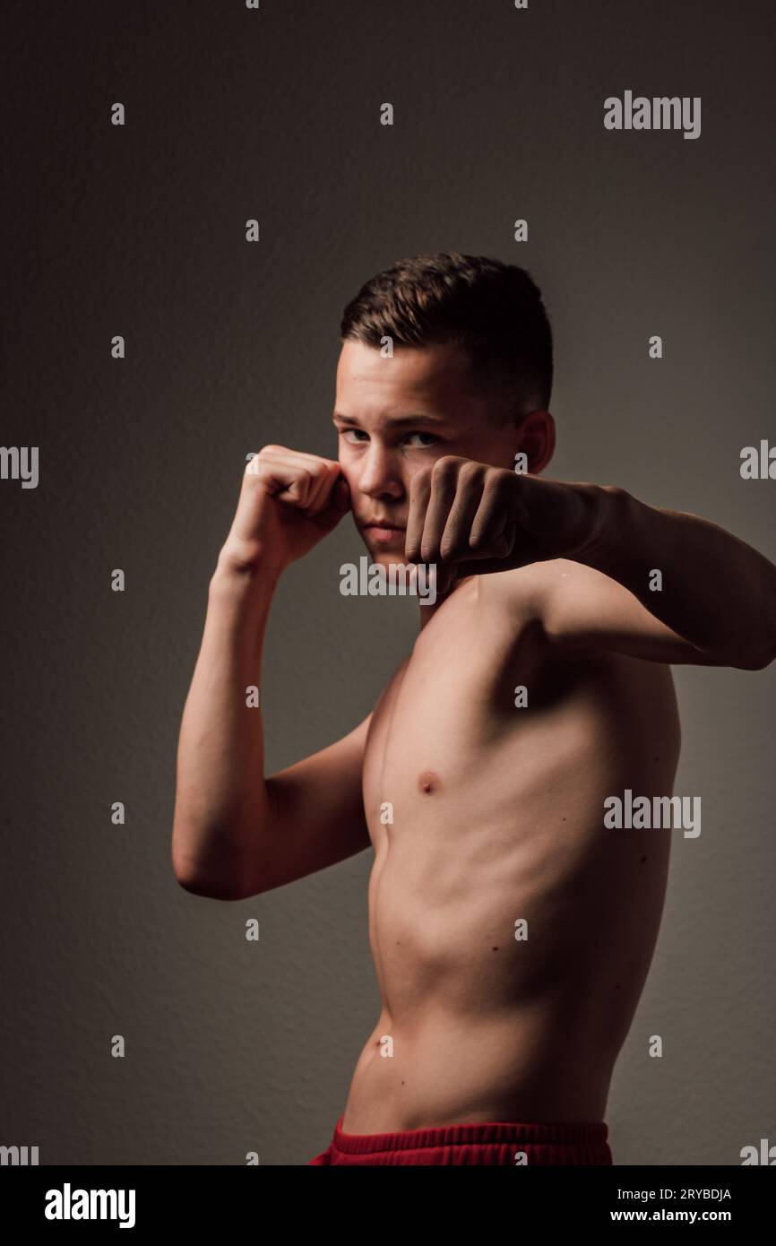 A teenage boxer athlete is training to box on dark background ...