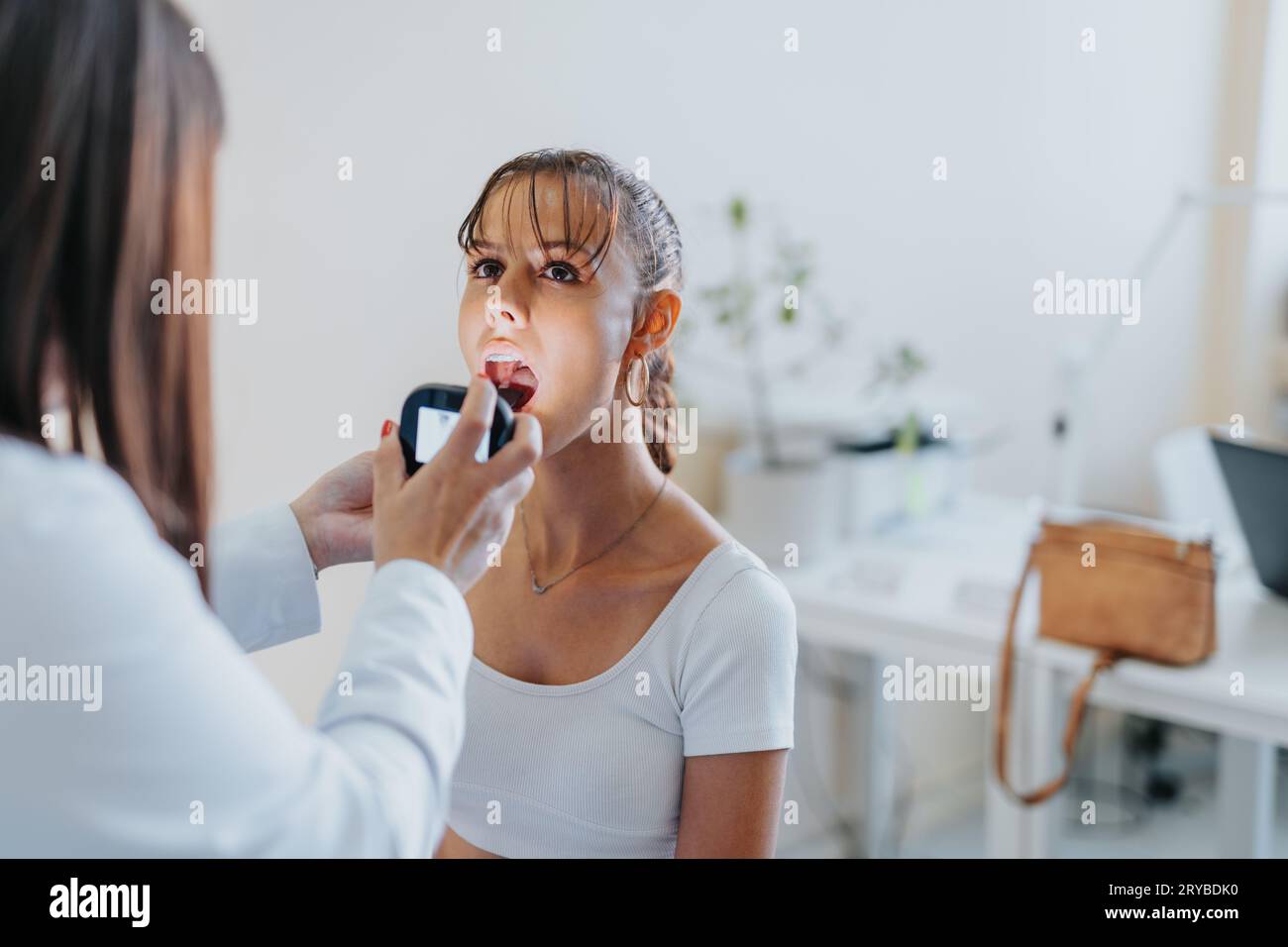A doctor checks throat of a young patient in a clinic using video ...