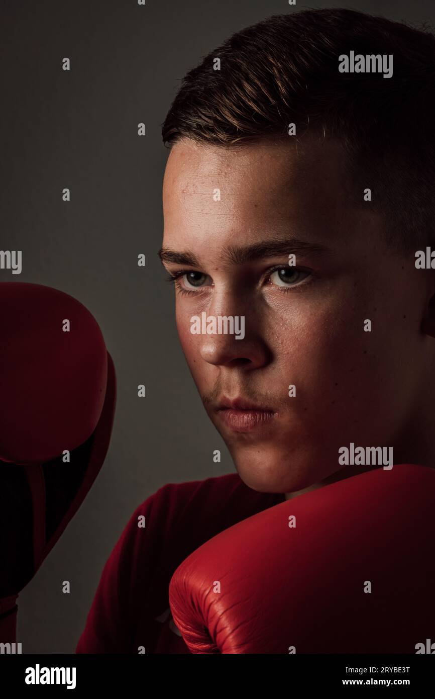 A teenage boxer athlete is training to box on dark background ...