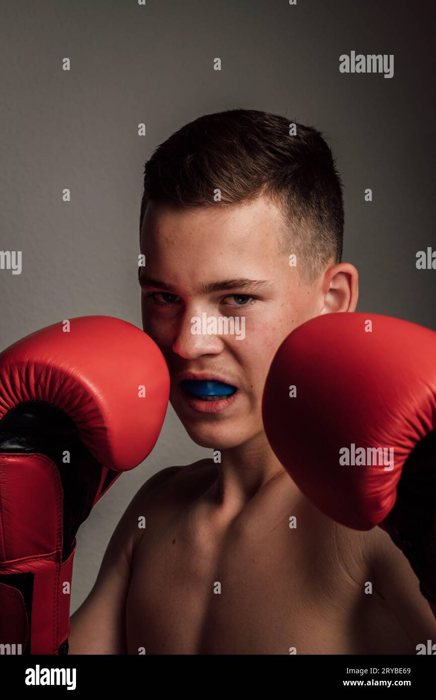 A teenage boxer athlete is training to box on dark background ...