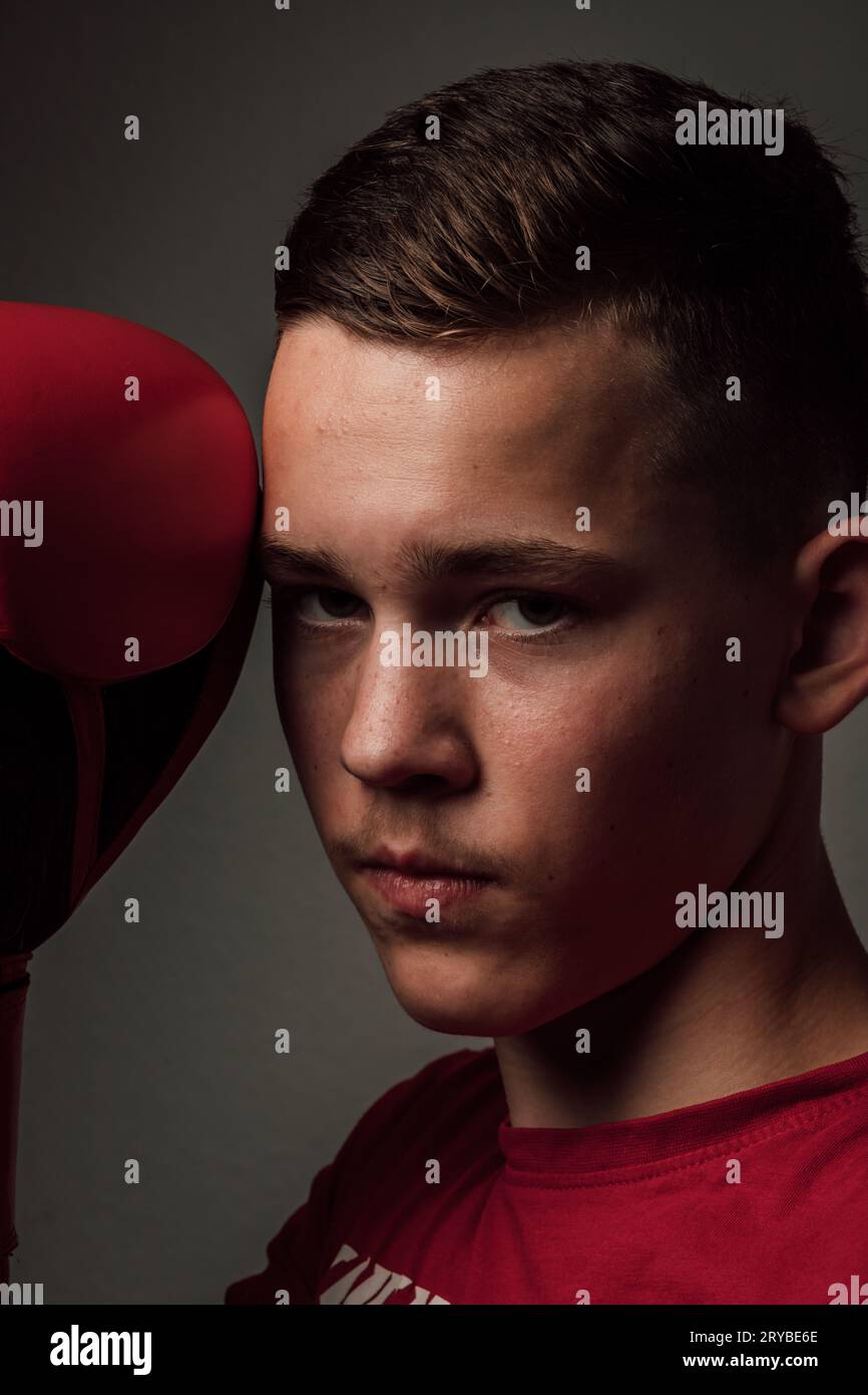 A teenage boxer athlete is training to box on dark background ...