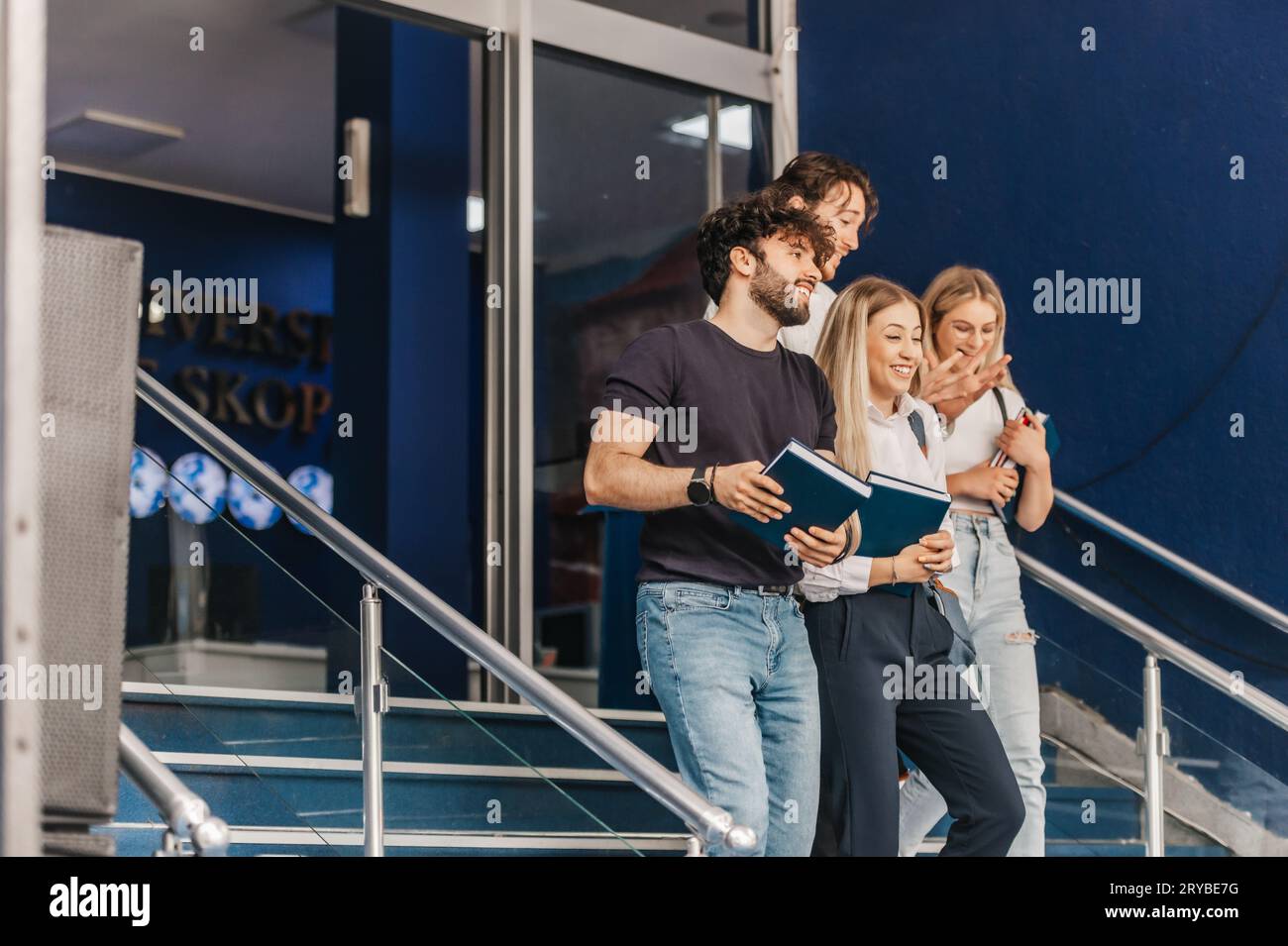 A group of students exiting their college, talking and smiling with ...
