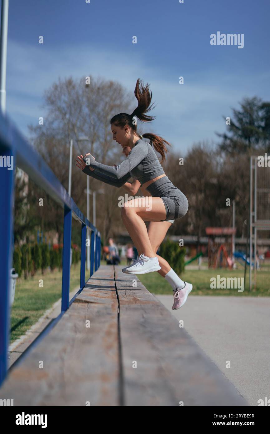 Sportsgirls exercising legs. They are doing jumps on the bench in the ...