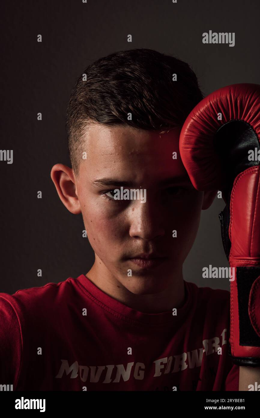 A teenage boxer athlete is training to box on dark background ...