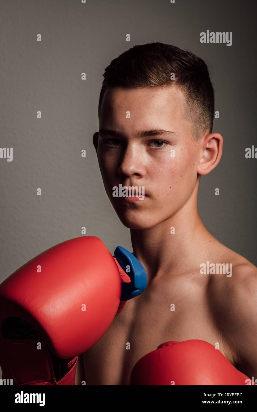 A teenage boxer athlete is training to box on dark background ...