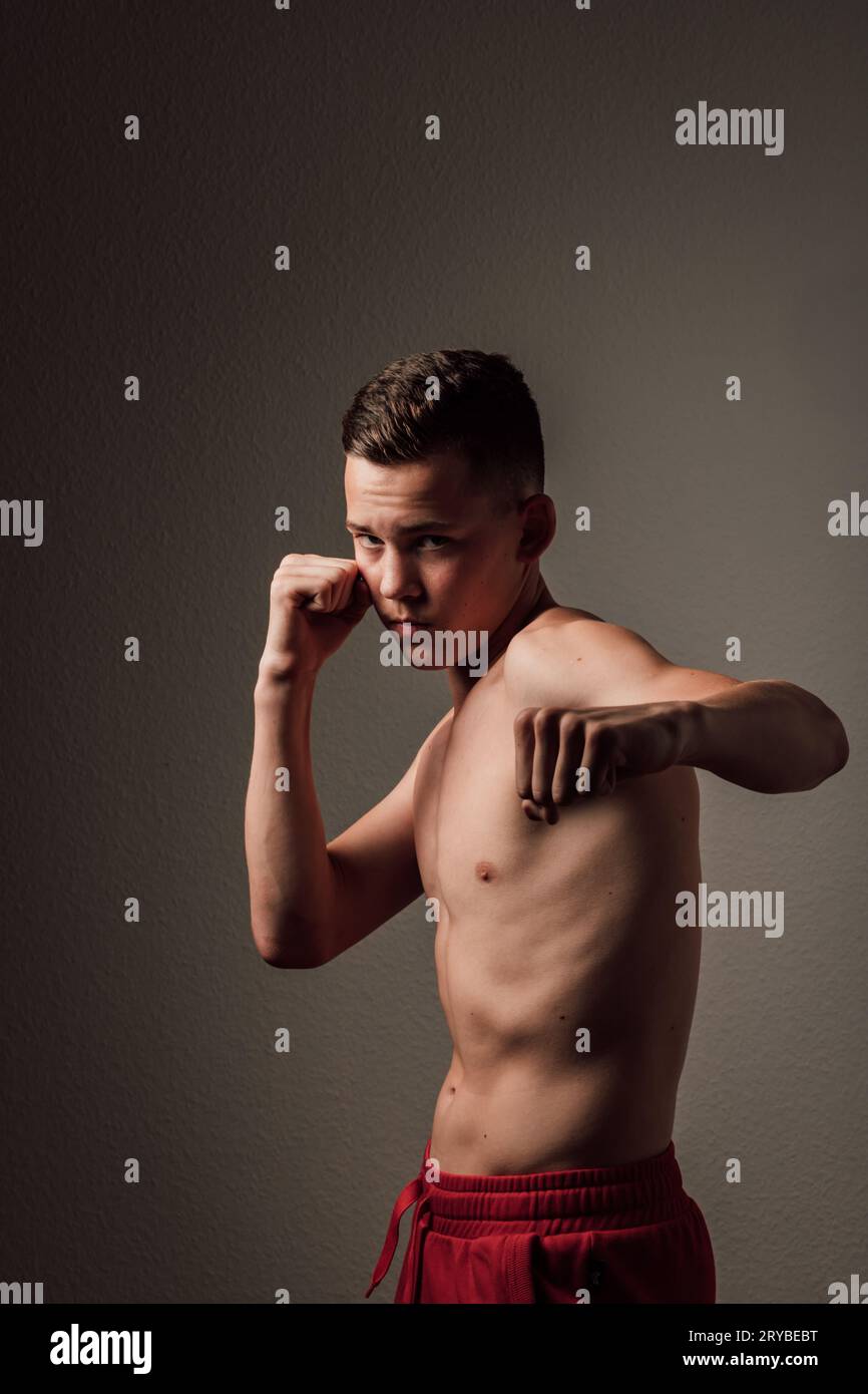 A teenage boxer athlete is training to box on dark background ...